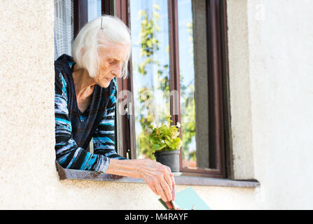 Senior woman receiving retirement check on the window at home Stock ...