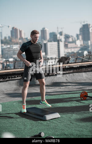 Sporty young man using step machine in gym Stock Photo - Alamy