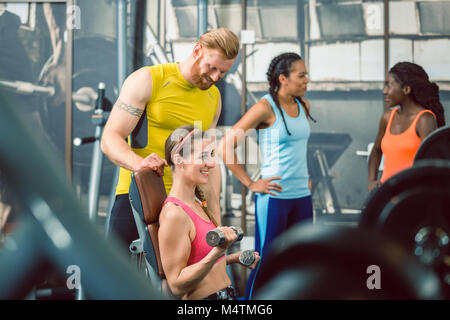 Side view of a handsome personal trainer guiding his client at the gym ...