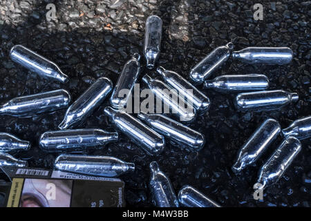 Nitrous Oxide gas canisters discarded on a street corner. Small silver ...