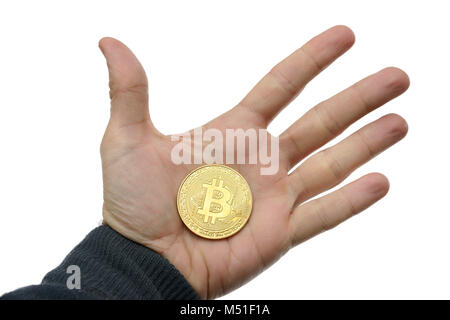 Golden Bitcoin token coin palm of a male hand with green nature ...