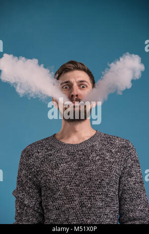 Handsome man vaping against blue background Stock Photo - Alamy