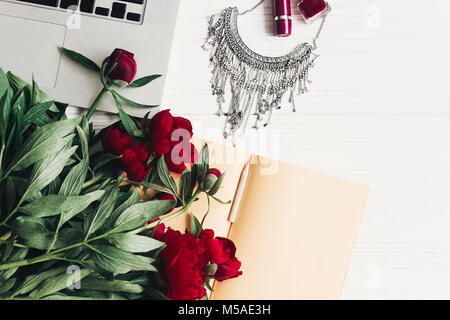 laptop with notebook, stylish necklace, lipstick, nail polish and ...