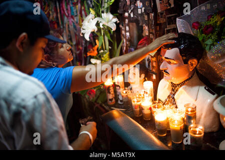 A man and woman pray to the statue of Jesœs Malverde in Culiac‡n ...