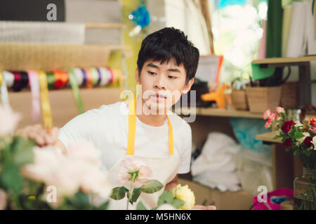 Young chinese man florist smiling confident using smartphone at flower ...
