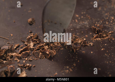 cutting industrial block of dark chocolate with knife, closeup photo ...