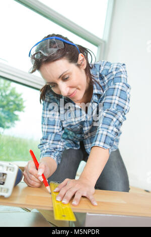 Female worker marking where to cut wood with circular saw Stock Photo ...