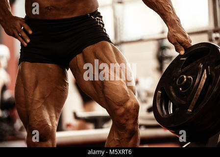 Close-up of bodybuilders muscular legs. Athlete man doing workout ...