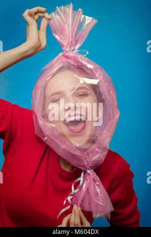 fun girl with head inside candy wrapper on blue background Stock Photo ...