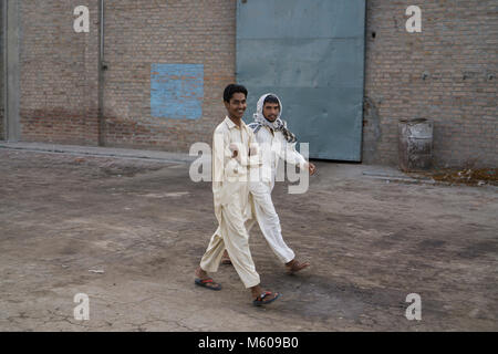 Men in Pakistani salwar kameez dress gather under arch of colonial ...