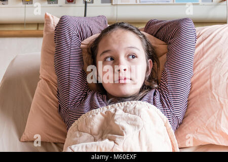 Asian American tween girl lying in hospital bed, health care concept ...