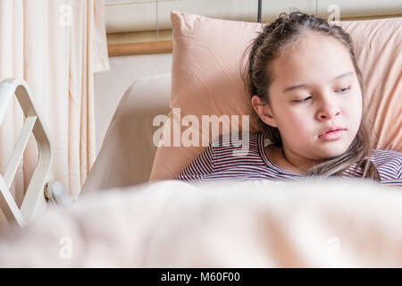 Asian American tween girl lying in hospital bed, health care concept ...