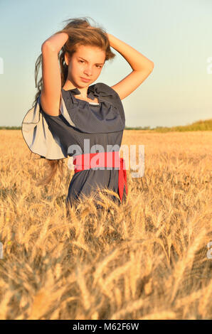 A field of golden barley stands under a blue sky with white clouds. A ...