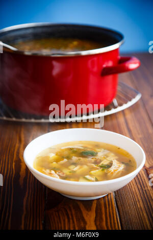 Pea soup in plate and pot, bread and salt shaker on red striped ...