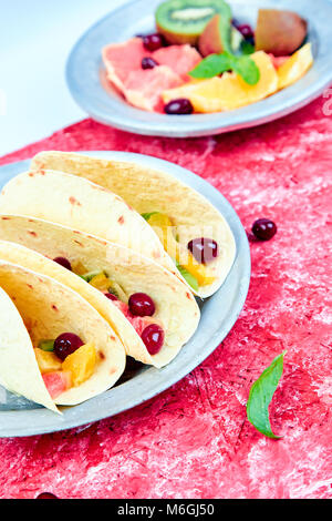 Fruit tacos with orange, kiwi, grapefruit red background and berry ...