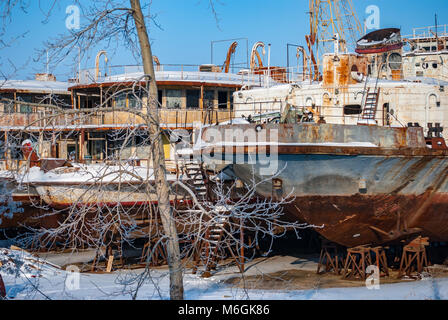Old rusty ferries located near snowy shore of harbor against cloudless ...