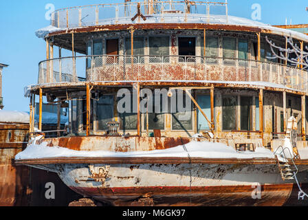 Old rusty ferries located near snowy shore of harbor against cloudless ...