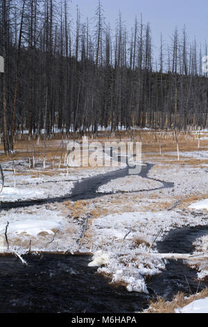 Frozen fast-flowing river through snow-covored rocks and stones in the ...