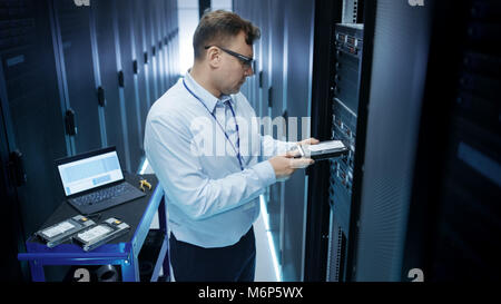 IT Engineer Installing Hard Drives into Working Rack Server. He's ...