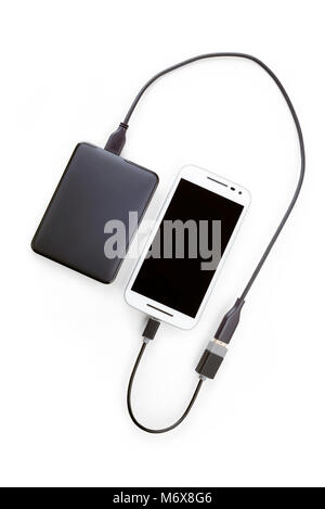 White smartphone connected to a black hard disk drive with an OTG cable ...