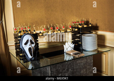 cheese snack, plates, cutlery, scary mask arranged on glass table on ...