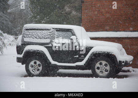 A Jeep wrangler covered in snow at sunset on a cold winter day Stock ...