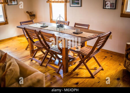 A wooden dining table set with empty plates indoor. Restaurant interior ...