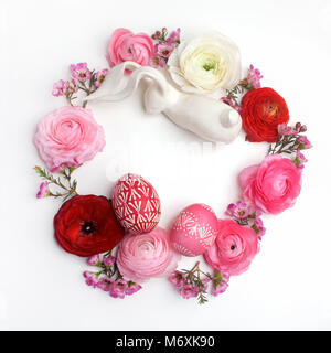 Easter eggs and ranunculus flowers frame on white background. Flat lay ...