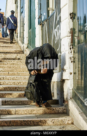 Old woman walking bent over with a stick at a market in northern ...