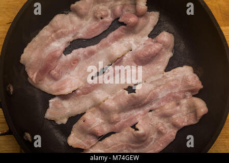 Streaky bacon cooking in the frying pan Stock Photo - Alamy