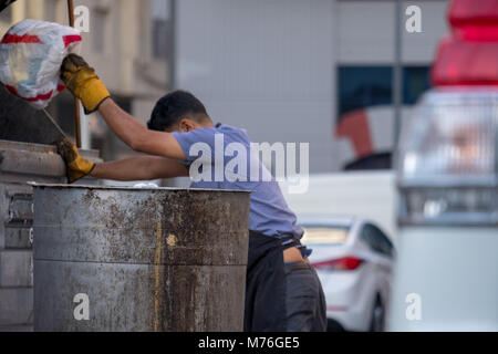 A young man throwing grabage into trash bin while wearing face mask ...