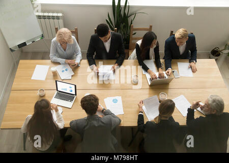 Multiracial business people working together at boardroom table at ...