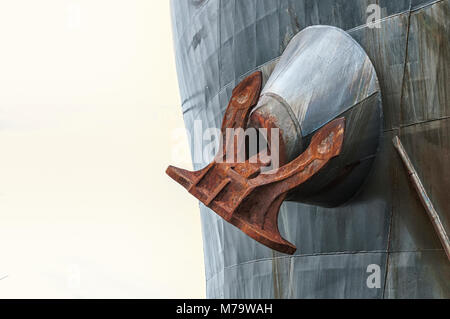 A close - up view of a ship's anchor housed in it's hawse pipe recessed ...
