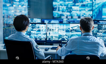 Security System Operator Looking At CCTV Footage At Desk In Office ...