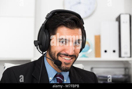 Portrait of spanish man dispatcher who is talking with client in office ...