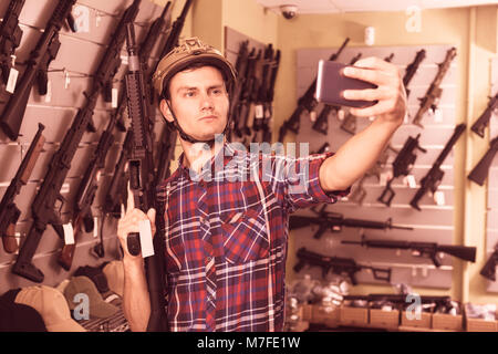 Serious young guy taking selfie with rifle in army store Stock Photo ...