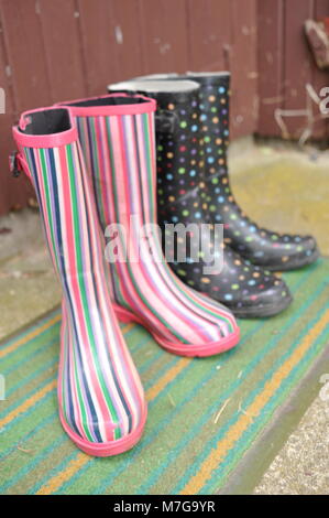 Two pairs of colorful women farmer or gardener boots on a mud mat by ...