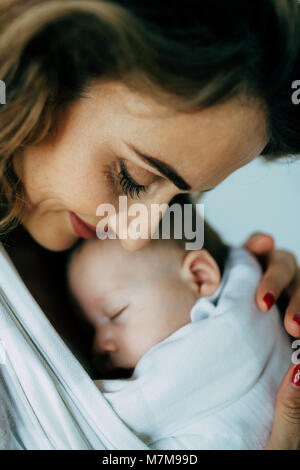A tender moment between a mother and her son as they hug affectionately on a striped sofa The ...