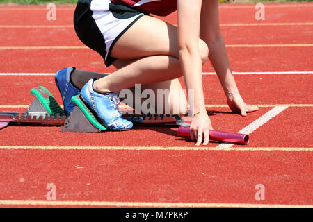 Runner in the starting blocks with baton Stock Photo - Alamy