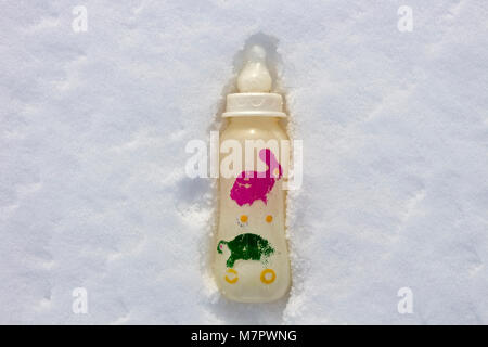 A frozen bottle of milk in snow, in which the cream has expanded and ...