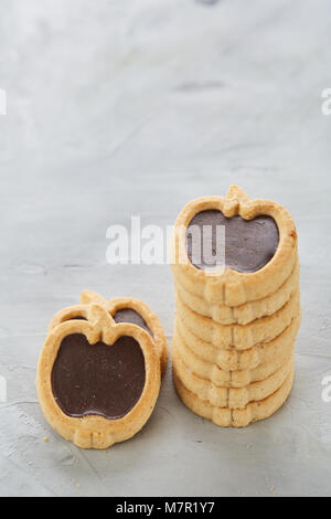Sweet apple shaped cookies arranged in rows on light textured ...