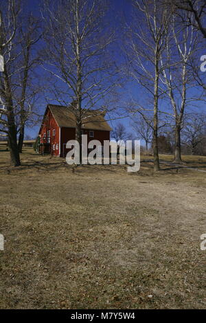 A rural scene with a red barn and a pole with a power line. The sun is ...