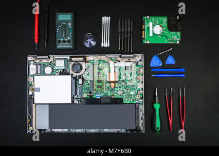 Disassembled laptop with computer parts and special tools for repair on ...