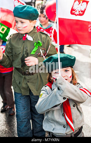 A small Polish scouting girl marches and holds the Irish flag during ...