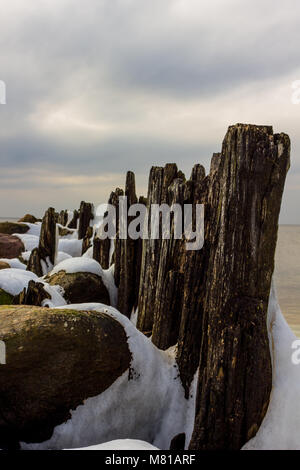 Jetty Pillars and Rocks Covered witn Snow in a Cloudy Winter Day with a ...