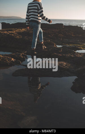 Beautiful beach with a woman walking over the cliff Stock Photo - Alamy