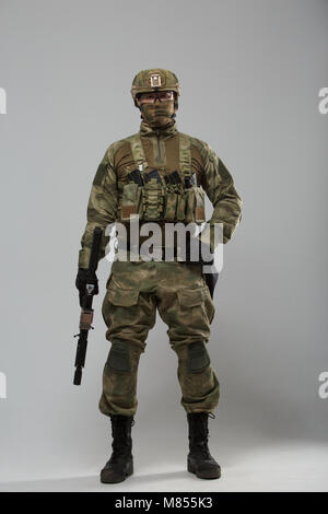 A military officer in full tactical gear and helmet stands with an ...