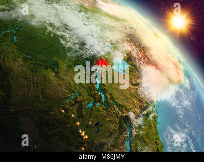 Sunrise above Rwanda highlighted in red on model of planet Earth in space with visible country ...