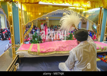 Sikh wedding ceremony in a Gurdwara with priest waving Chaur Sahib (fly ...