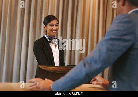 Friendly welcoming female receptionist helping tourist with check-in ...